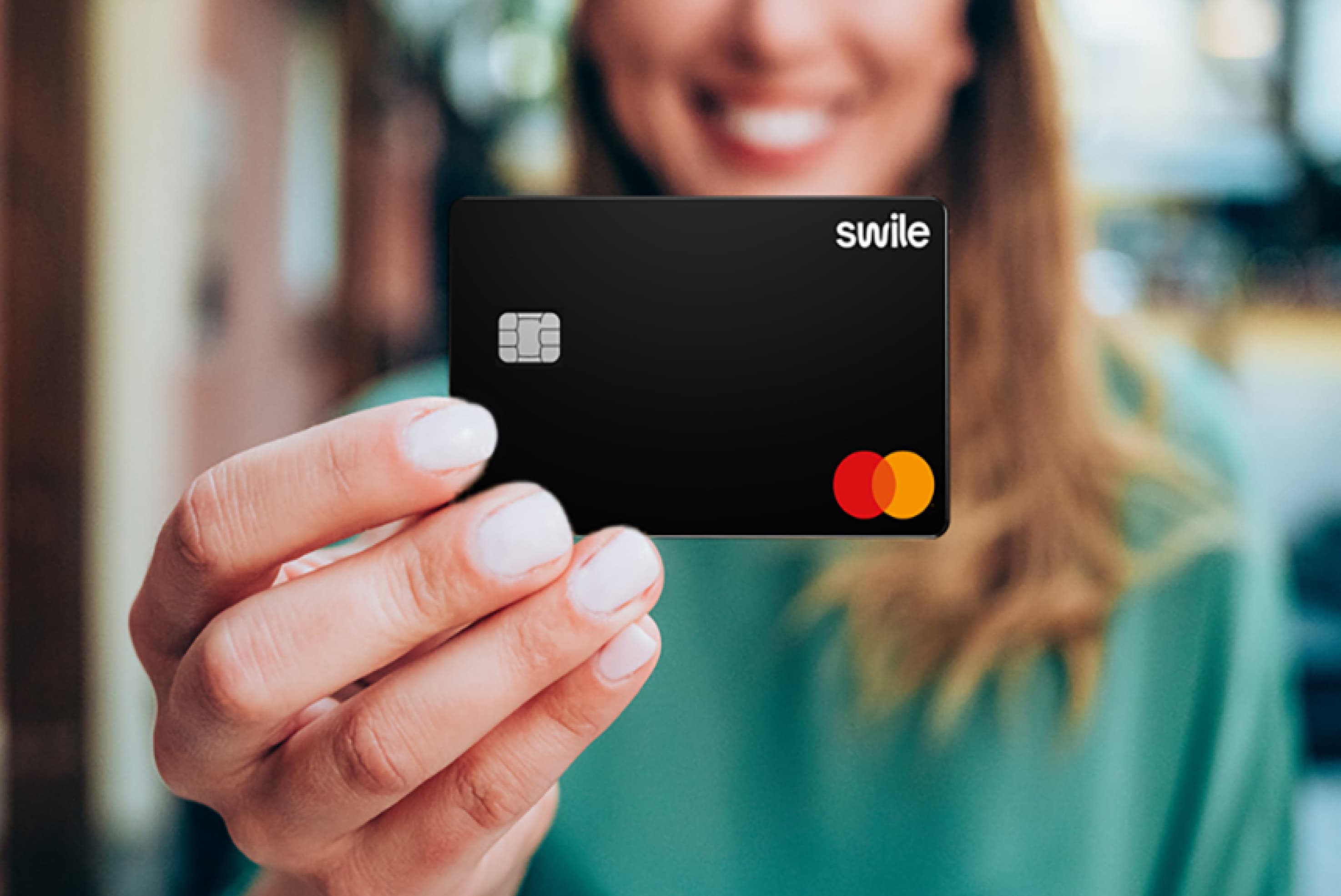 Mulher sorrindo de boca aberta, segurando e olhando o cartão da Swile