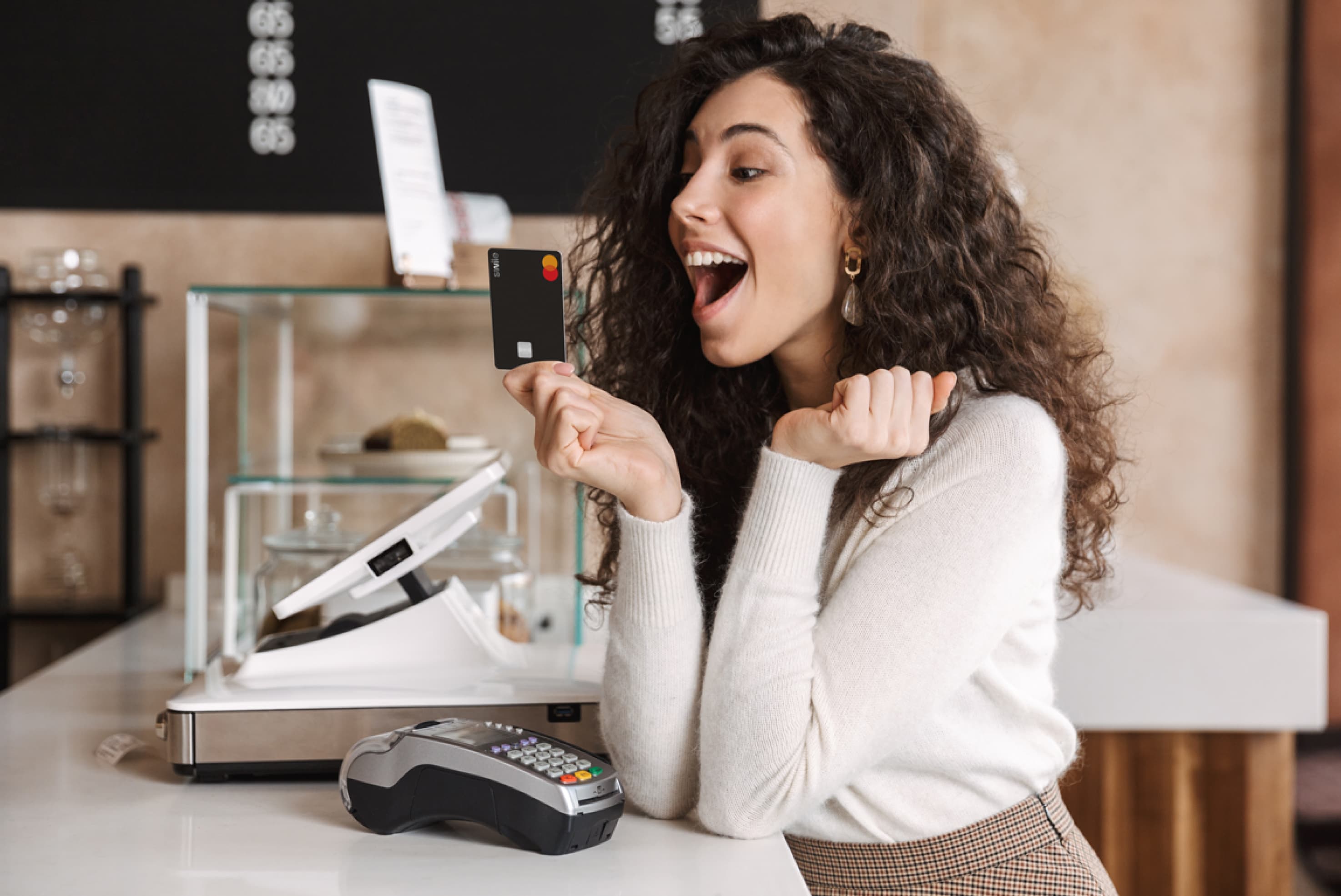 Mulher sorrindo de boca aberta, segurando e olhando o cartão da Swile